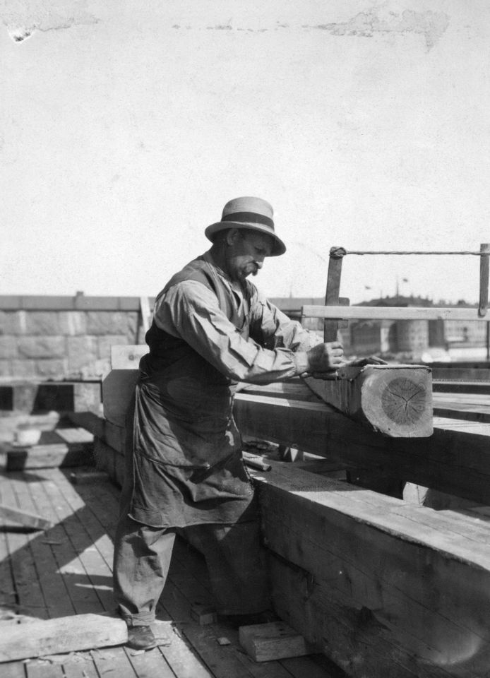 Timmerman Aronsson i arbete med en timmerstock vid Stadshusbygget ...